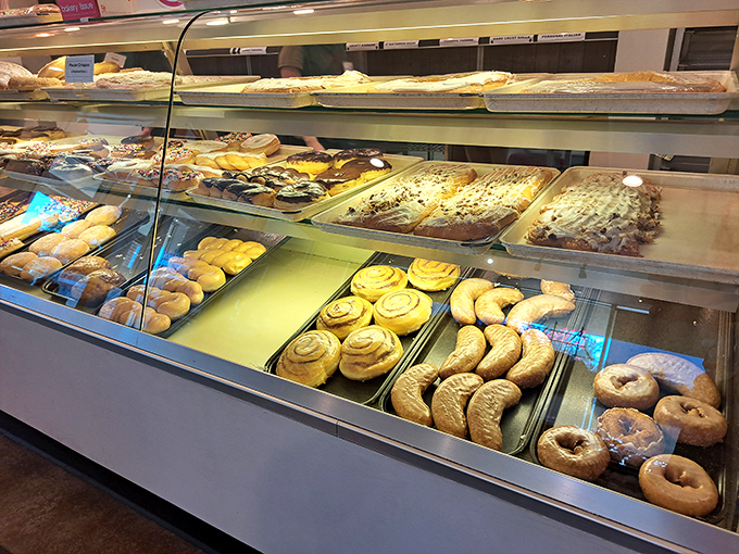 Cinnamon rolls spiral like edible galaxies while sheet cakes promise celebrations—this counter holds more happiness than most therapy sessions.