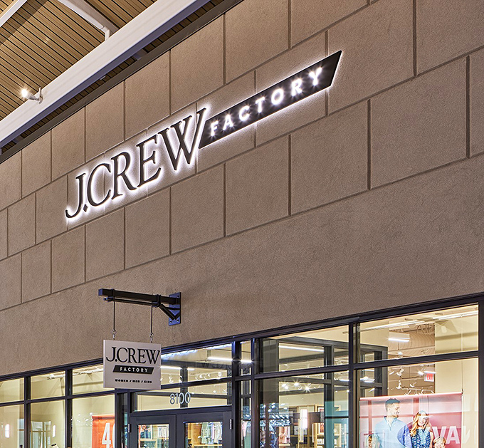 J.Crew Factory's illuminated signage glows like a beacon for preppy fashion enthusiasts seeking that perfect cable-knit sweater at half the price.