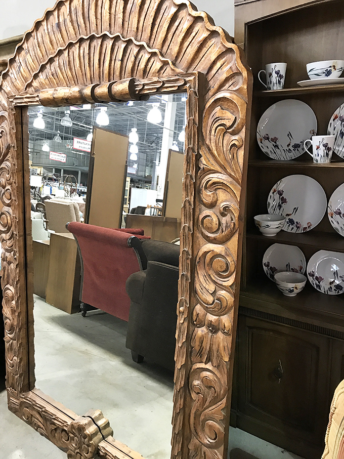 An ornately carved mirror that would cost a fortune in an antique shop waits patiently for someone who appreciates its golden grandeur.