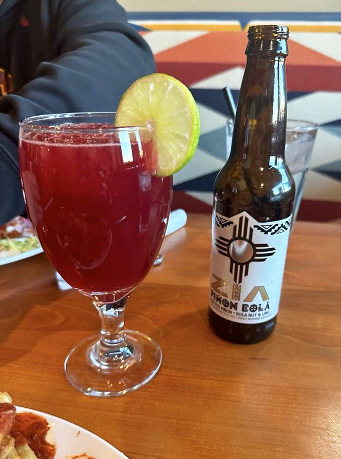 That vibrant red prickly pear mojito isn't just a drink&mdash;it's liquid New Mexico, served alongside a Zia-emblazoned soda that screams local pride.