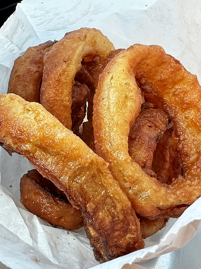 These onion rings aren't just side dishes; they're golden halos of crispy perfection that deserve their own moment of silent appreciation.