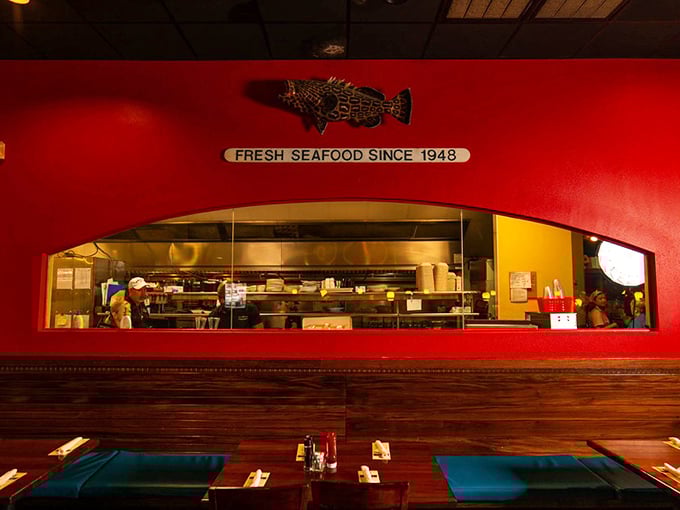 The open kitchen pass-through window offers a glimpse of the culinary magic happening behind that signature red wall.