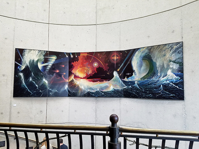 A swirling cosmic seascape painting captures the drama of waves meeting stars. The curved wall installation pulls you into its vortex of color and movement.