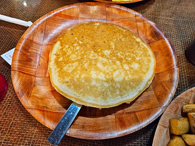 One perfect pancake, golden as a Louisiana sunset, waiting patiently on its wooden throne for a baptism of syrup. 