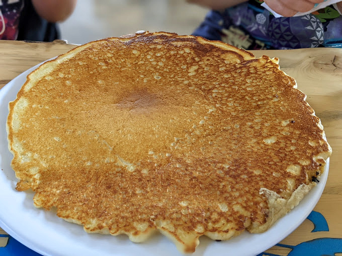 A pancake so large it needs its own zip code, golden and ready to absorb enough syrup to float a boat.