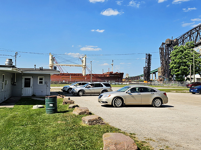 The parking lot view reveals the true Michigan experience—great food with a side of Great Lakes shipping, as freighters pass in the background.