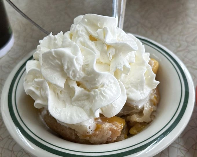 Peach cobbler topped with a cloud of whipped cream&mdash;Georgia's official dessert, unofficially improved by being served warm enough to melt your resolve.