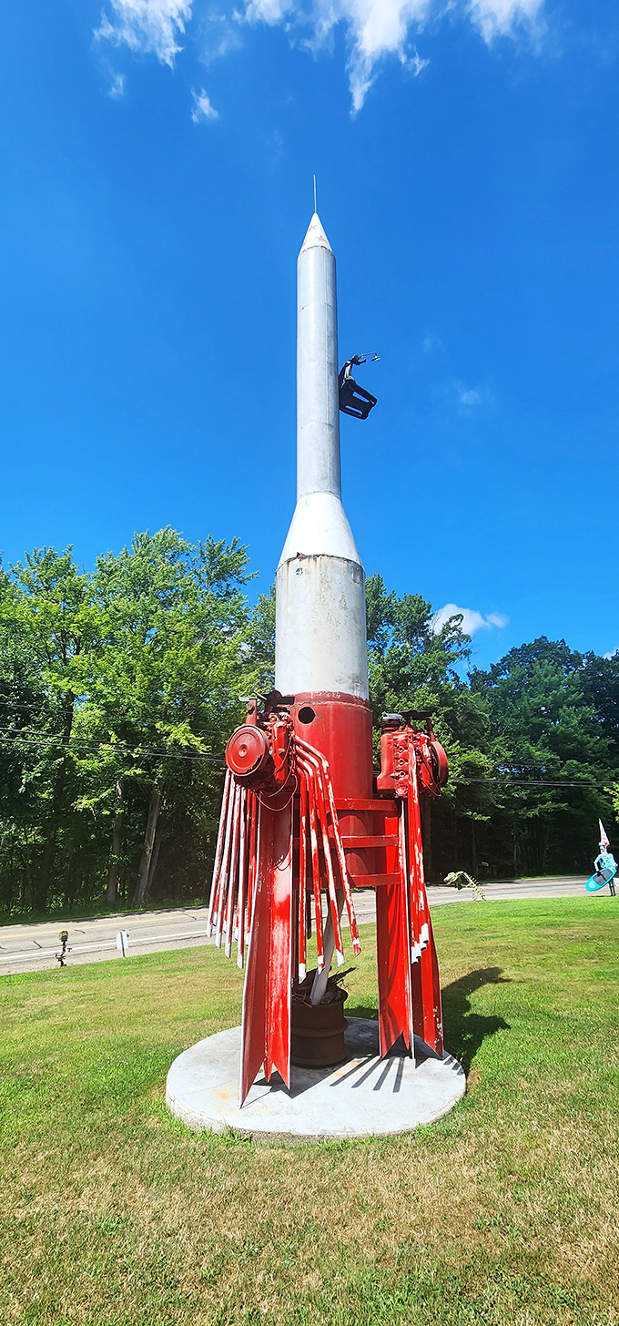 Reaching skyward with red-white-and-blue ambition, this rocket sculpture transforms scrap metal into space-age dreams against a perfect summer sky.