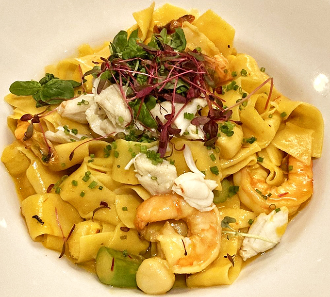 Seafood pappardelle that's a celebration on a plate: plump shrimp and delicate crabmeat nestled among ribbons of pasta, topped with fresh microgreens.