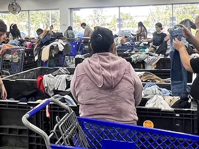 The beautiful chaos of discovery. Shoppers dive deep into textile bins, where yesterday's fashion becomes tomorrow's vintage find.