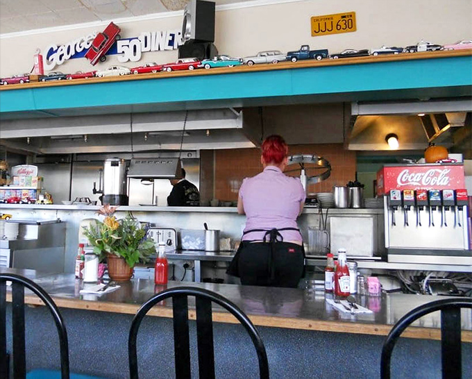 Where the magic happens—a glimpse into the choreographed dance of diner service, with model cars standing guard above the kitchen pass.