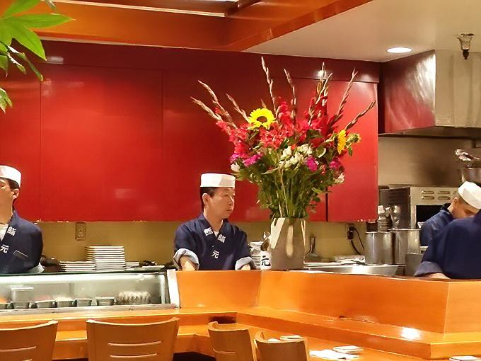 Behind the counter, chefs in traditional garb work with flower-like precision, their movements as choreographed as their stunning floral arrangements.