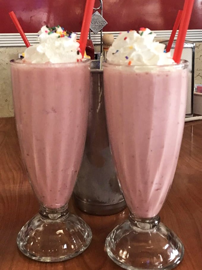 Twin strawberry shakes standing proud like the dessert version of synchronized swimmers. Those red straws are just begging you to start the flavor race.