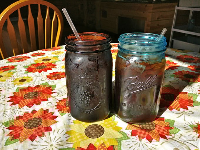 Mason jars of sweet tea on a flowered tablecloth &ndash; the unofficial state beverage of South Carolina served with a side of nostalgia.