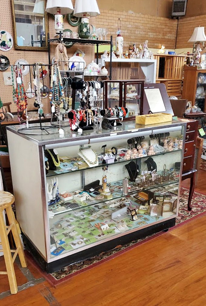 Jewelry and trinkets glimmer in this vintage display case, surrounded by the warm glow of antique lamps and decorative treasures.