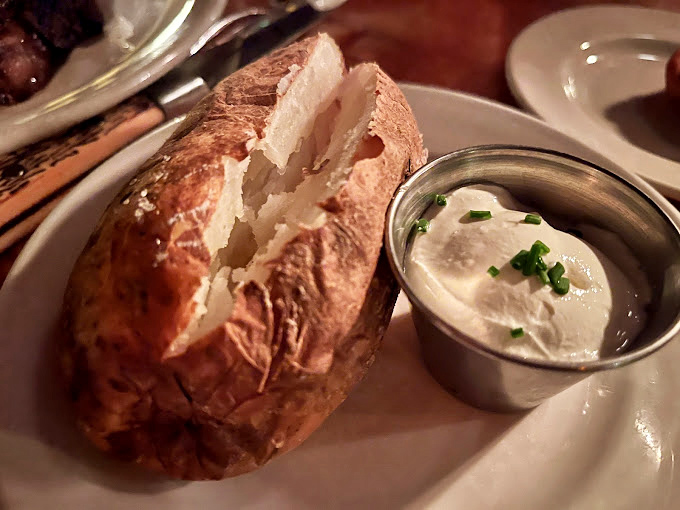 Not just a baked potato &ndash; a fluffy cloud of starchy perfection accompanied by its soulmate: a metal cup of sour cream sprinkled with chives.