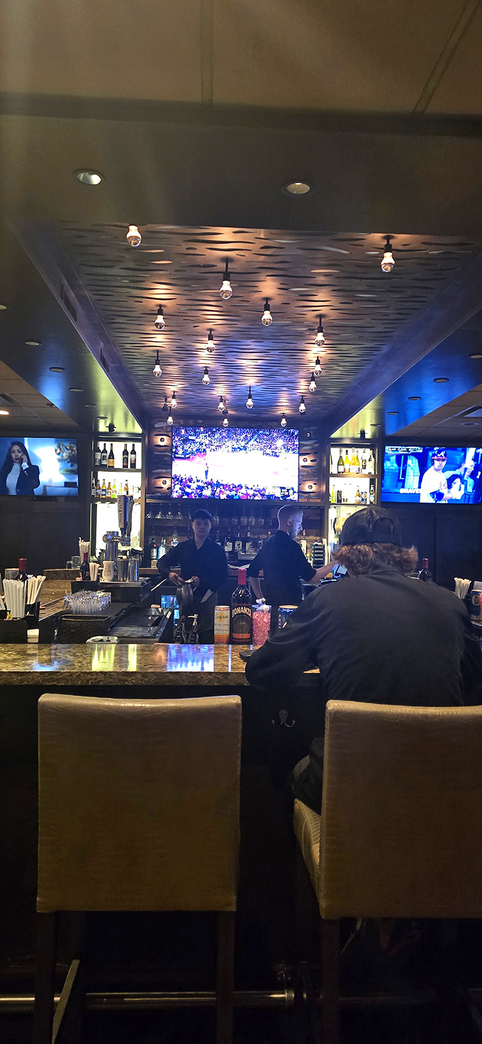 The bar area balances sports-watching practicality with date-night ambiance&mdash;Edison bulbs overhead and game-day action on screens create the perfect compromise.
