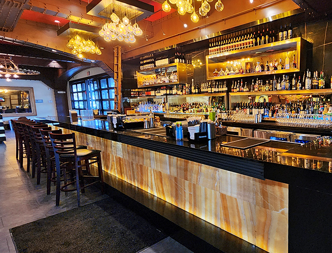 The bar gleams with amber-lit bottles like a library of liquid possibilities. Each shelf promises a different adventure for your taste buds.