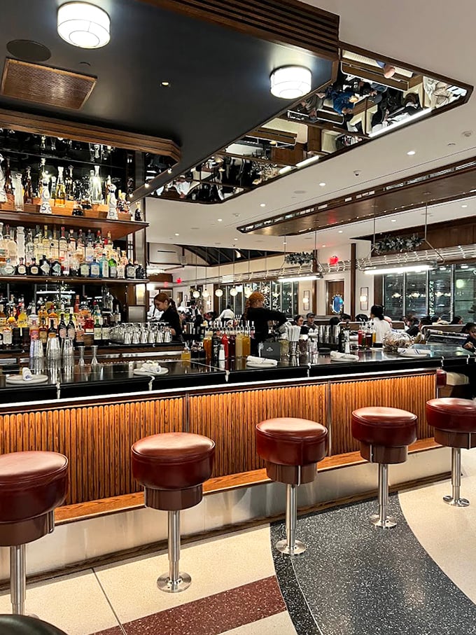 The bar gleams with promise and possibility, its mirrored ceiling reflecting both the impressive spirits selection and the life choices that led you to order that second cocktail.