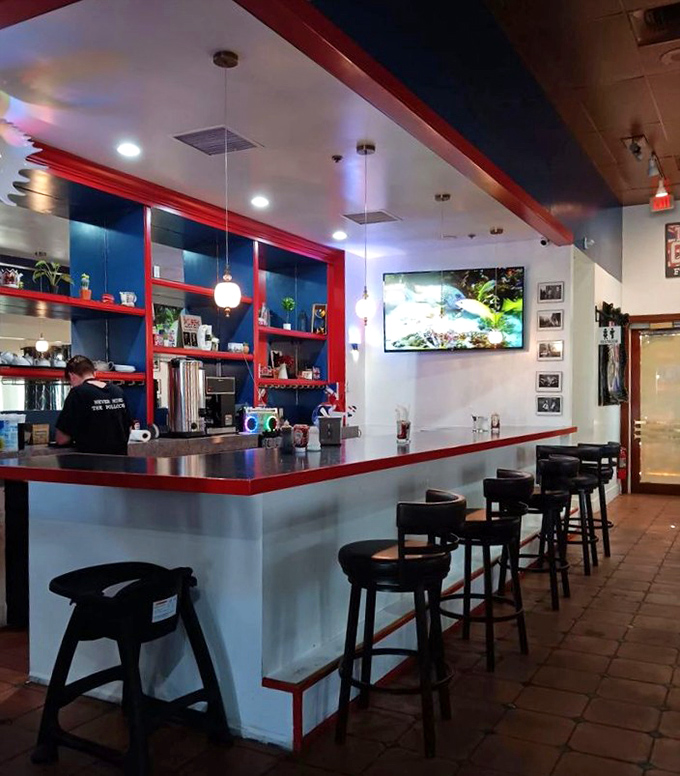 The counter where fish dreams come true. Red and blue accents frame the kitchen pass, where golden-battered treasures emerge like Olympic champions.