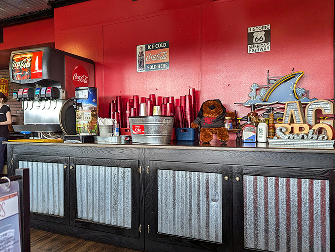 The beverage station keeps things simple: cold drinks, condiments, and BBQ memorabilia creating authentic roadhouse vibes throughout.