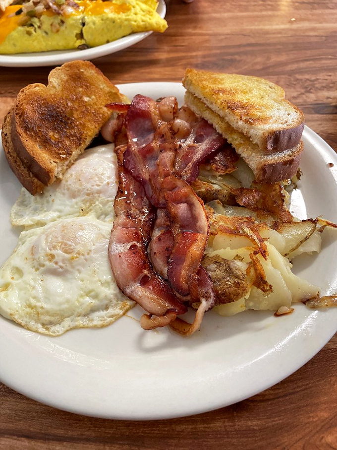 The breakfast platter of champions: perfectly cooked eggs, crispy bacon, golden hashbrowns, and toast. Morning glory on a plate.