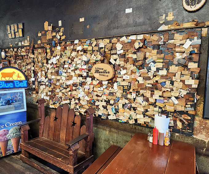 Thousands of business cards papering the walls like a smoke-stained guest book. Each rectangle a testament from someone who came, saw, and devoured.