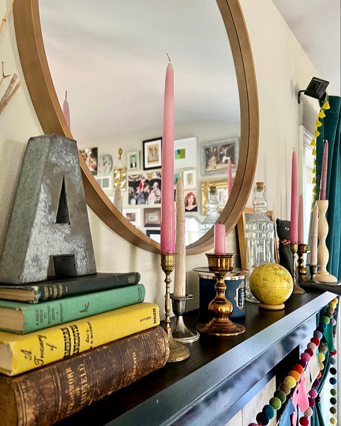 A vignette worthy of a Wes Anderson film set&mdash;vintage books, brass candlesticks, and that perfect circular mirror for your next selfie.