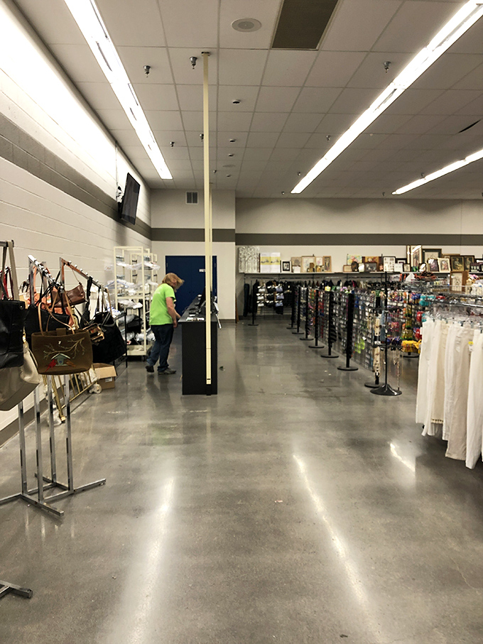 An employee in green arranges merchandise&mdash;the unsung hero of the organized chaos that makes thrifting possible.