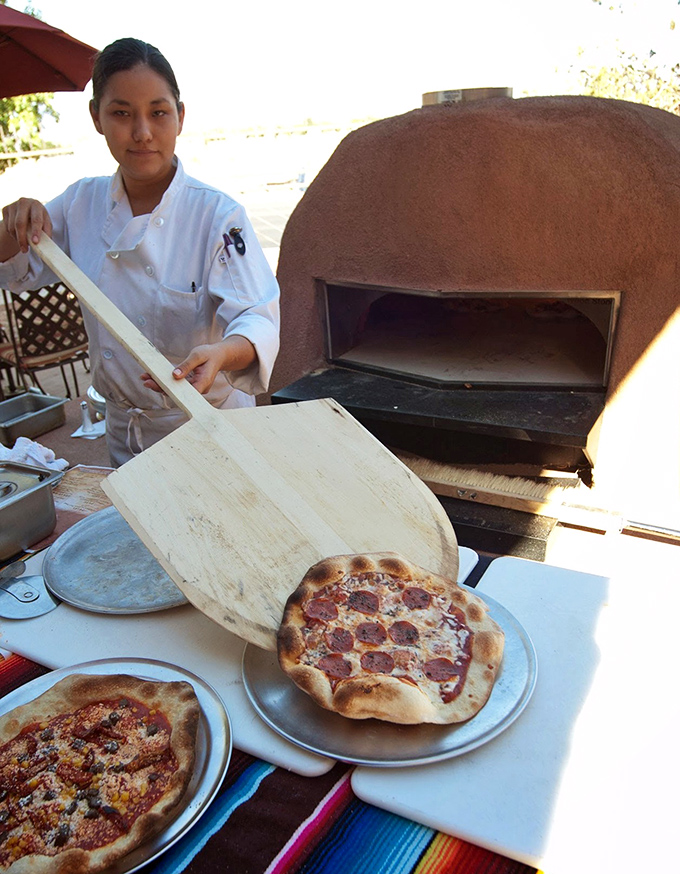 Where tradition meets innovation: a chef works the outdoor horno oven, pulling perfect flatbreads from its earthen depths just as Pueblo bakers have for centuries.