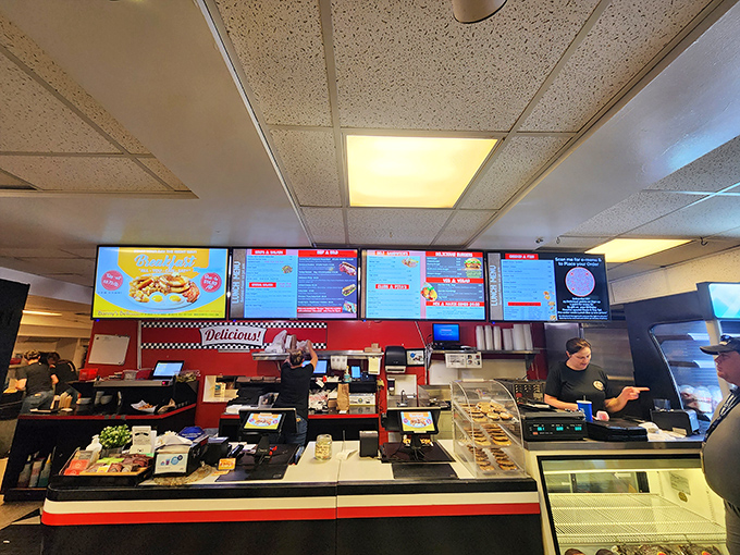 Behind the counter, digital menus glow above the workspace where sandwich dreams become delicious reality every day.