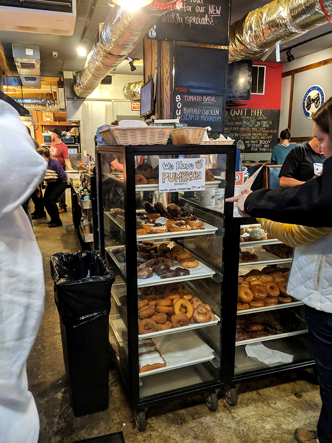 Donut display case: where willpower goes to die. Each shelf offers a different path to breakfast bliss.