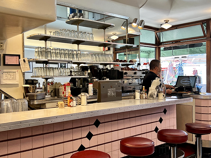 Where magic happens, one order at a time. The counter's pink tile and gleaming surfaces have witnessed countless coffee refills and life stories.