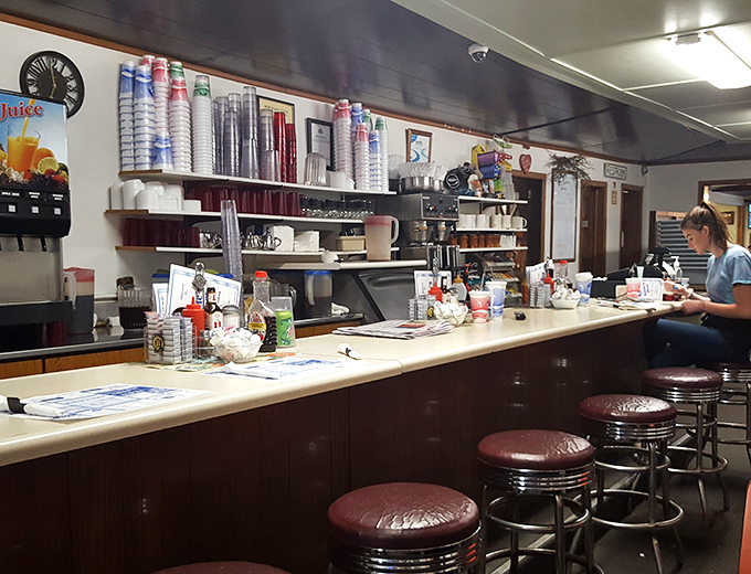 The counter where regulars perch like birds on a wire, watching the breakfast ballet unfold. Those burgundy stools have supported generations of happy eaters.