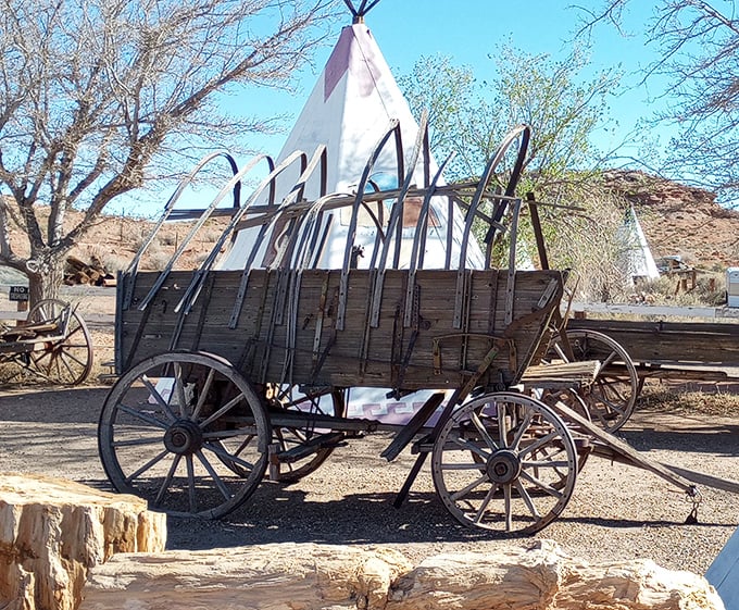 An antique covered wagon sits before the teepees&mdash;transportation evolution captured in one perfectly framed Arizona tableau.