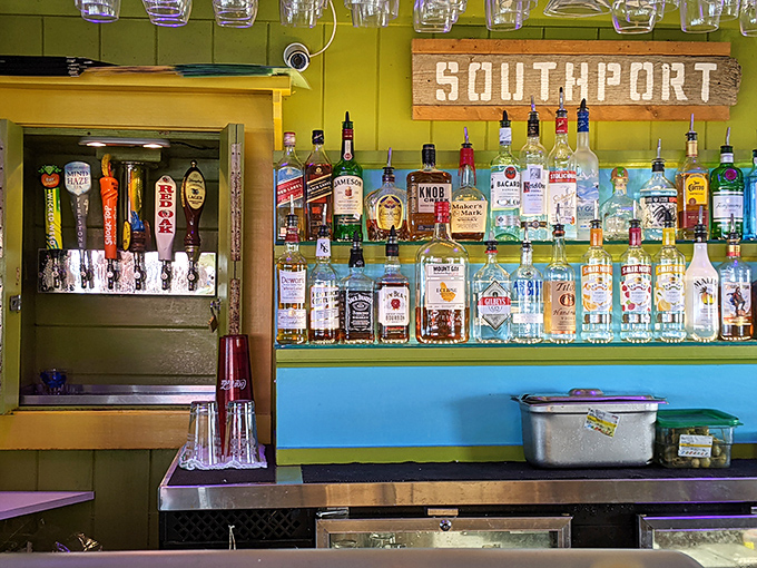 Behind this bar, bottles glow like a sunset against turquoise shelves, with a weathered "Southport" sign that's seen more toasts than a Sunday brunch.