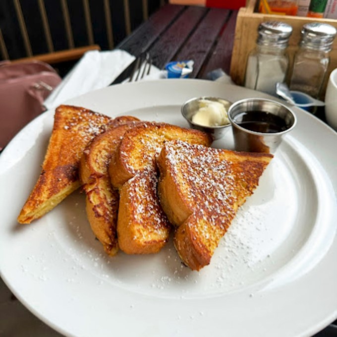 French toast that's crossed the line from breakfast to dessert, dusted with powdered sugar and waiting for that maple syrup baptism. Morning indulgence at its finest.