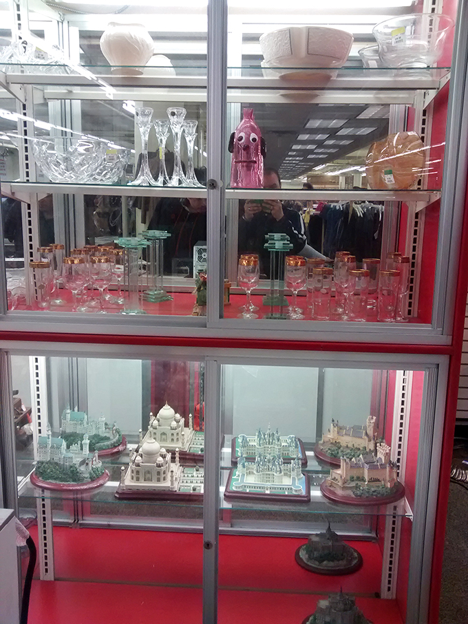 Crystal and collectibles gleam behind glass, miniature architectural wonders below&mdash;proof that one person's decluttering becomes another's discovered treasure.