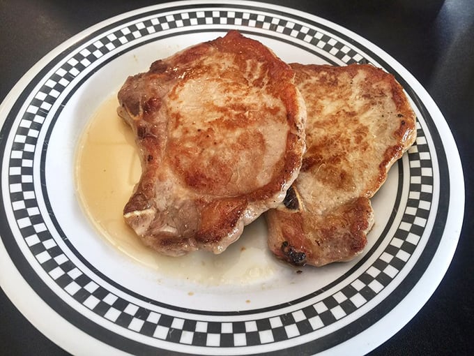 Pork chops seared to perfection, swimming in their own juices like they're enjoying a spa day before meeting their delicious destiny.