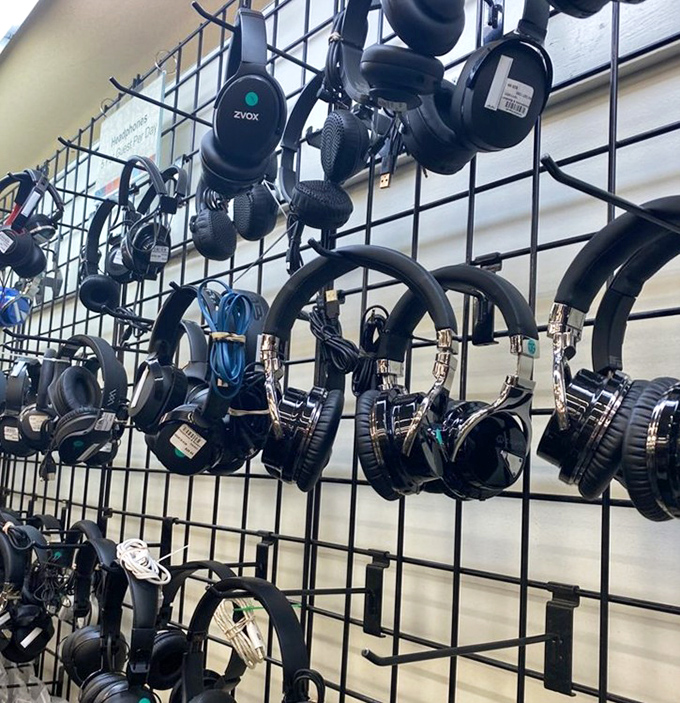 Headphones dangle like exotic fruit, waiting to be plucked. Audio equipment that once soundtracked someone else's journey now awaits yours.