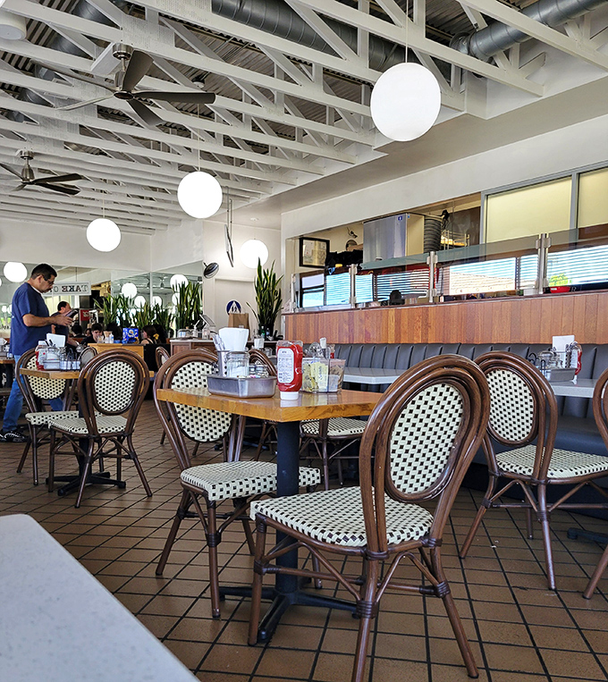 Bistro chairs meet diner booths in this bright space where plants add greenery and the ceiling height ensures your breakfast vibes can soar.