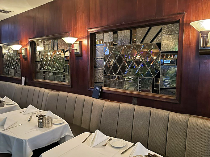 Diamond-patterned glass and rich wood paneling frame these booths like works of art. This isn't just a seat; it's your front-row ticket to culinary nostalgia.