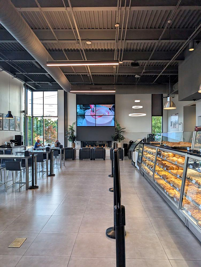 Display cases stretch toward infinity, filled with golden-hued temptations. The modern space feels like a temple dedicated to butter and sugar.