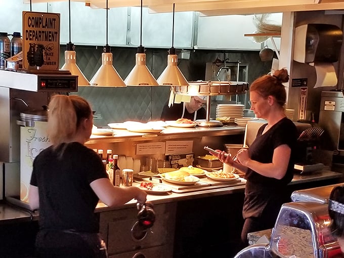 The kitchen pass—where breakfast magic happens. Notice the "Complaint Department" sign that's probably never needed in a place this good.