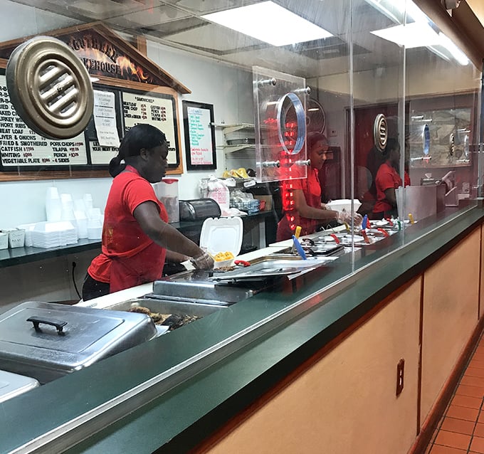 Behind the glass, culinary magic happens as staff in bright red shirts transform simple ingredients into legendary meals that haunt your dreams.