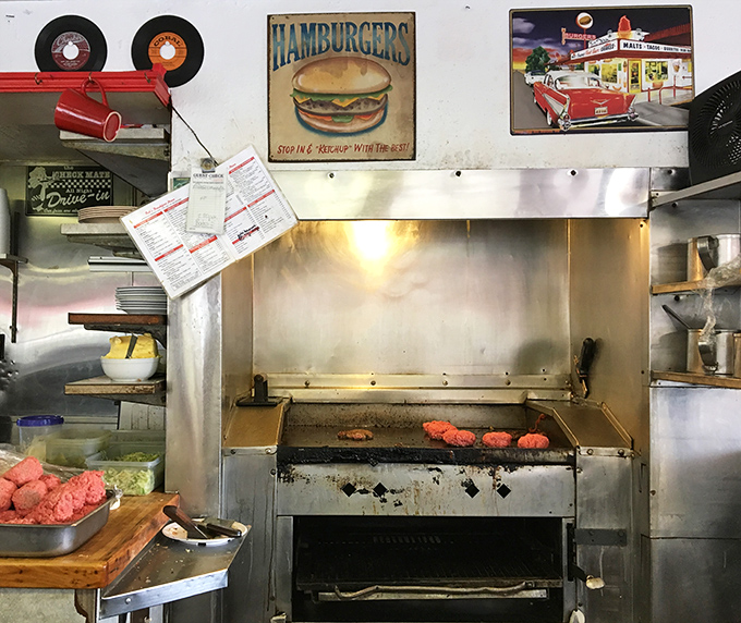 The sacred grill space where burger magic happens, complete with vintage signs that remind you this isn't their first burger rodeo.