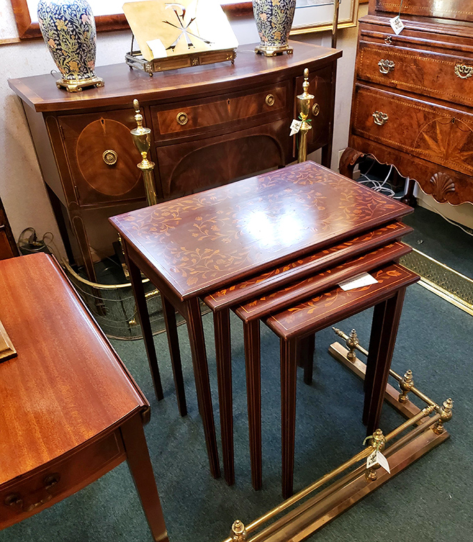 Nesting tables showing off their marquetry like peacocks, while a sideboard stands guard with brass accents gleaming like royal medals.