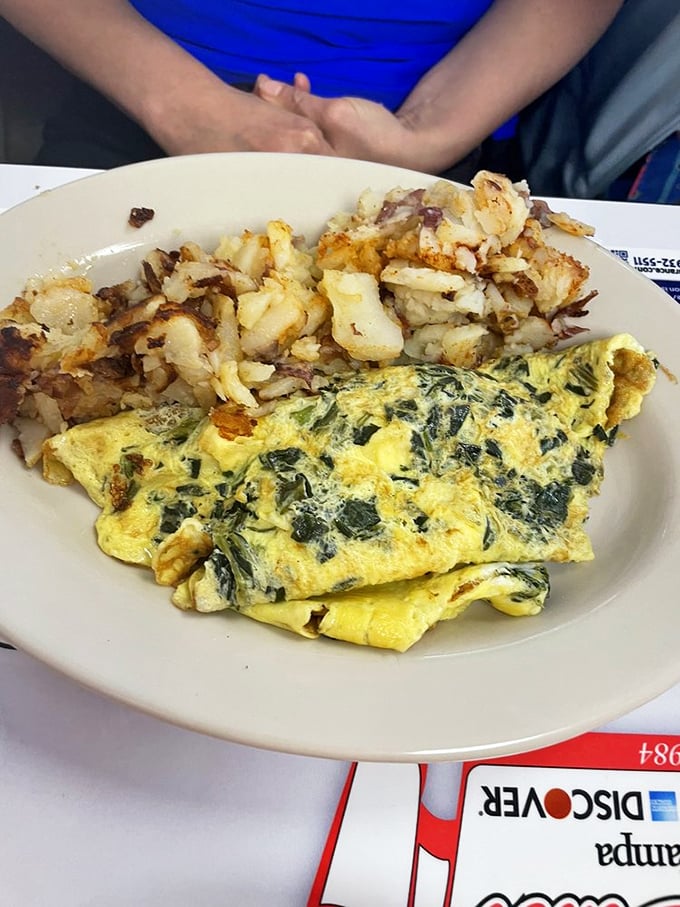 A spinach omelet that proves vegetables can be breakfast heroes too, especially when paired with home fries that crackle with each bite.