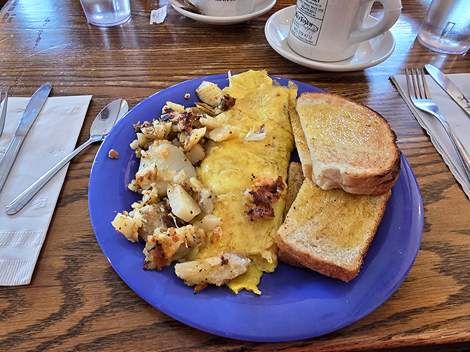 The breakfast trifecta: a fluffy omelet, crispy home fries, and toast that's achieved that perfect golden-brown state that toasters at home never quite manage.
