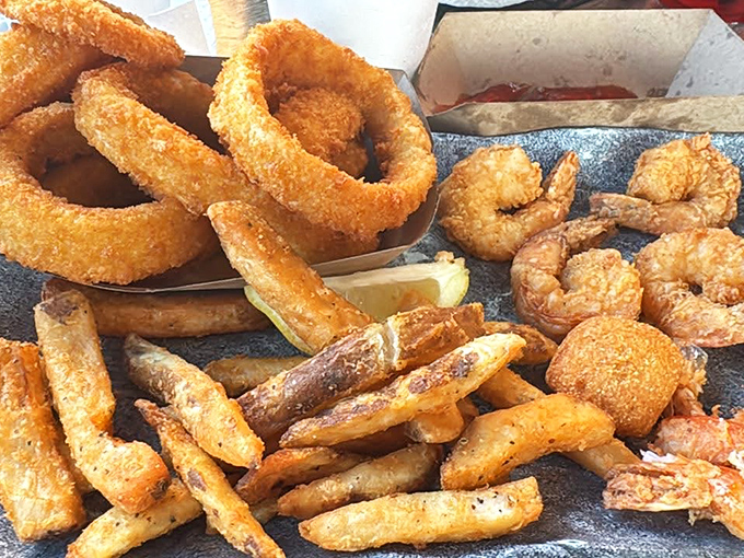 Golden onion rings tower alongside fried shrimp like crispy architecture, proving that carbs and seafood make beautiful music together always.